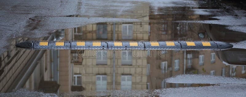 Black and Yellow Speed Bump in a Puddle on the Pavement Stock Image ...