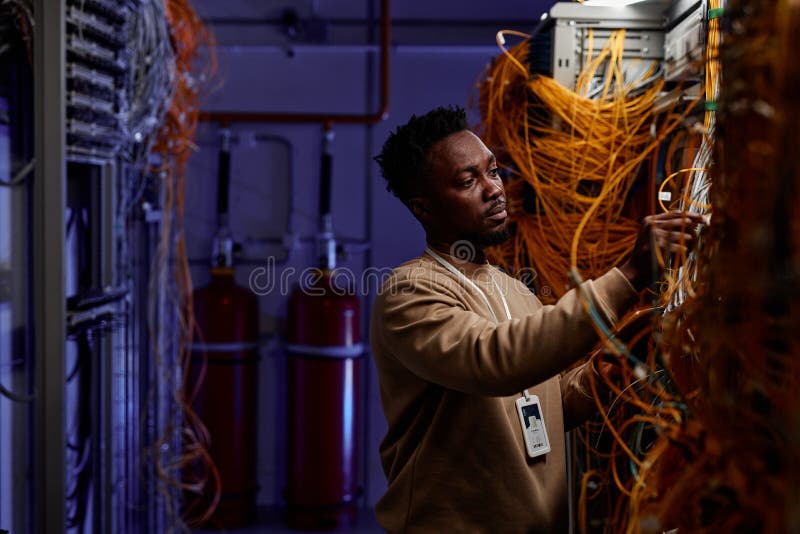 Black Young Man As System Administrator Working with Server in Neon ...