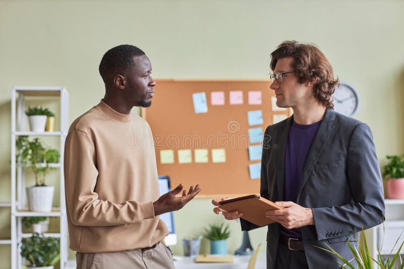 Black Young Man Talking To Colleague in Office Discussing Work Project ...