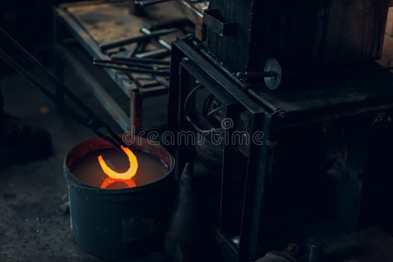 Blacksmith Forges and Tempering Metal Horseshoe in Jar with Water at ...