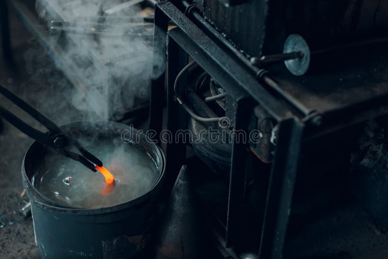 Blacksmith Forges and Tempering Metal Horseshoe in Jar with Water at ...