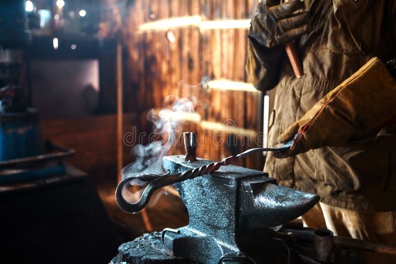 The Blacksmith Forging the Molten Metal on the Anvil in Smithy. Stock ...