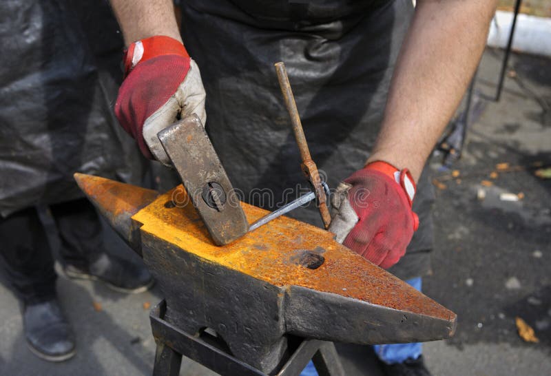 Blacksmith Hands Holding Forceps and a Hammer Forging a Metal Billet ...