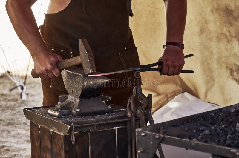 Blacksmith in a Leather Coat Works a Red-hot Piece of Iron with a ...
