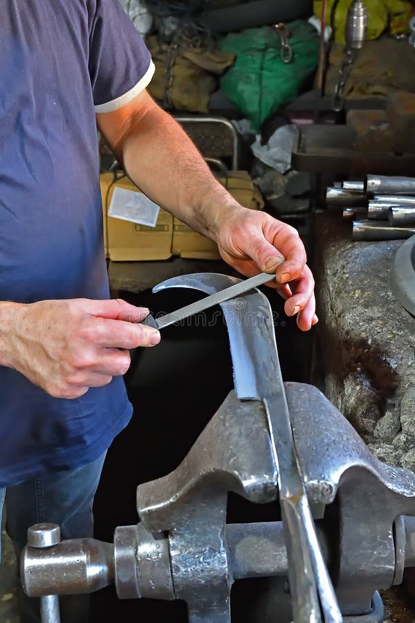 A Blacksmith Sharpens a Cutting Tool in a Blacksmith S Workshop. Stock ...