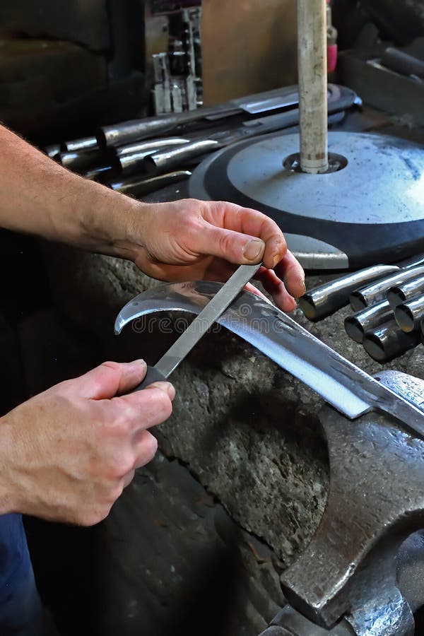 A Blacksmith Sharpens a Cutting Tool in a Blacksmith S Workshop. Stock ...