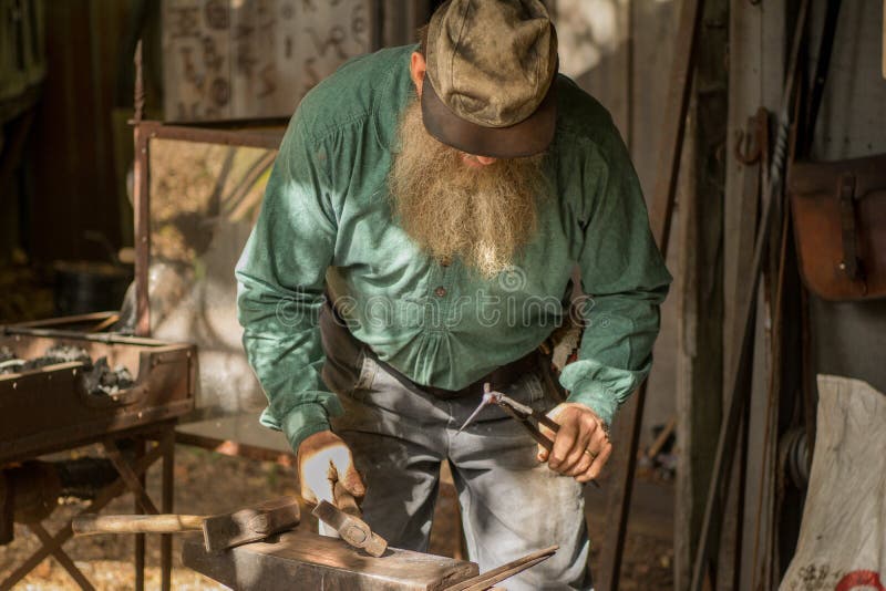 A Blacksmith Working Black Metal in a Historical 100 Year Old (smithy ...