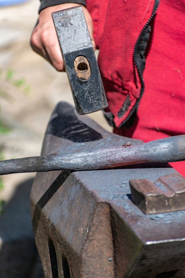 A Blacksmith Working a Piece of Iron while Working on an Anvil Stock ...