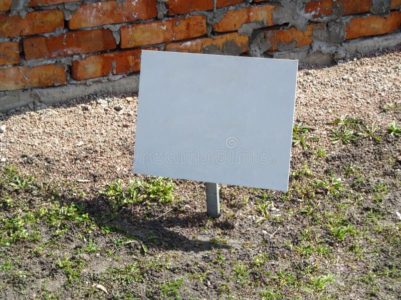 Blank Information Board Sticks Out of the Ground Against a Brick Wall ...