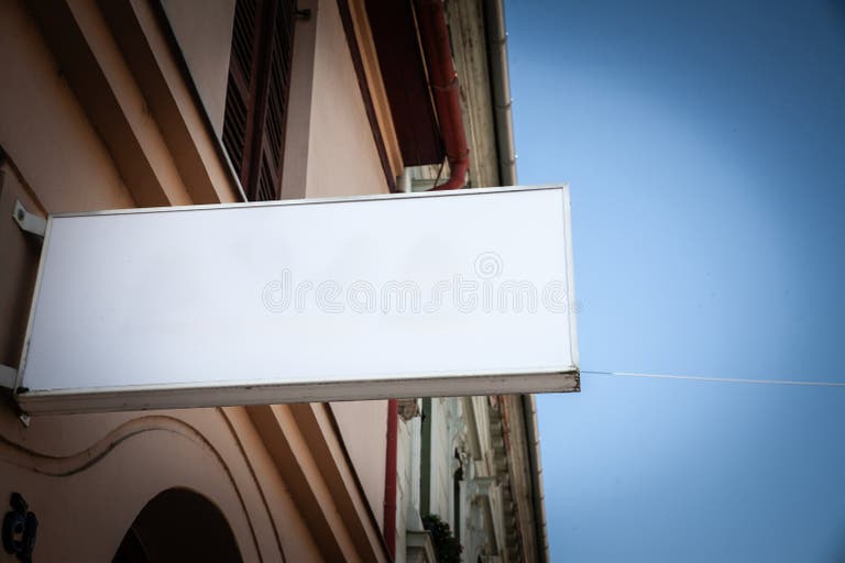 Blank Rectangular White Sign Juts from a Storefront, Offering Empty ...