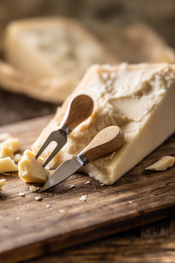 A Block and Pieces of Parmesan Cheese on a Cutting Board Along with a ...