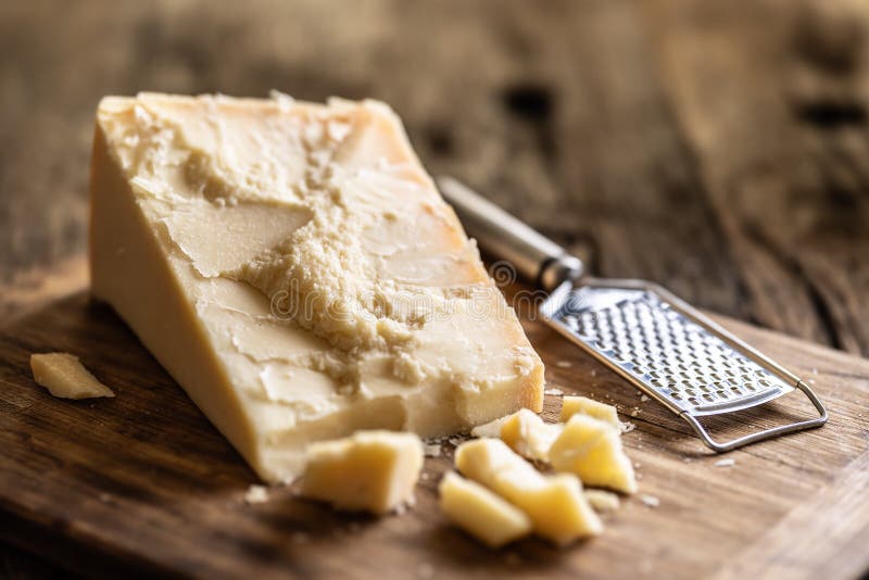 A Block and Pieces of Parmesan Cheese on a Cutting Board Along with a ...