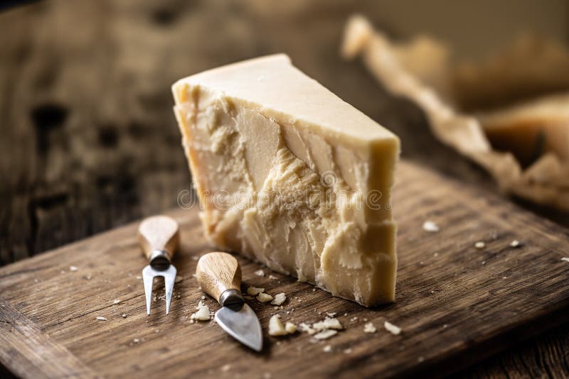 A Block and Pieces of Parmesan Cheese on a Cutting Board Along with a ...