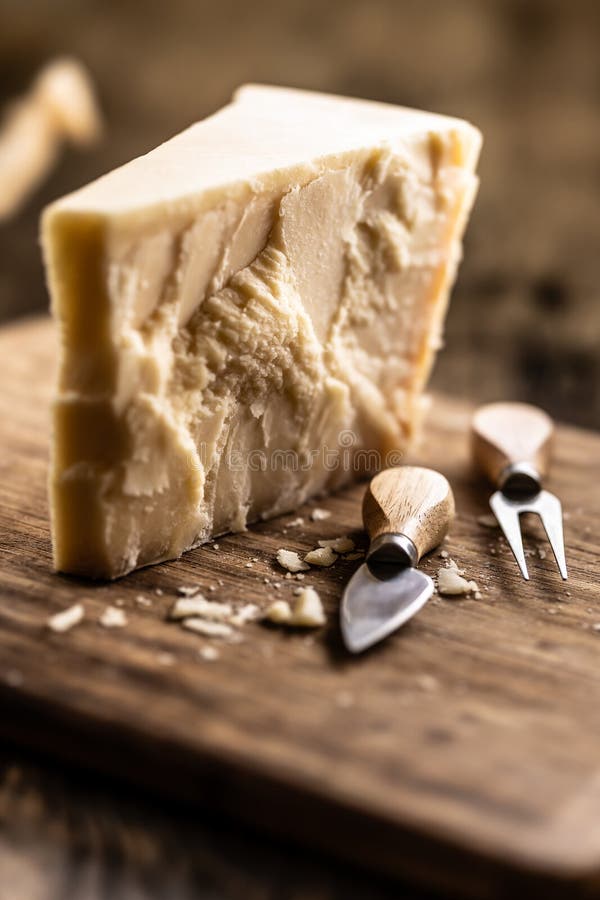 A Block and Pieces of Parmesan Cheese on a Cutting Board Along with a ...