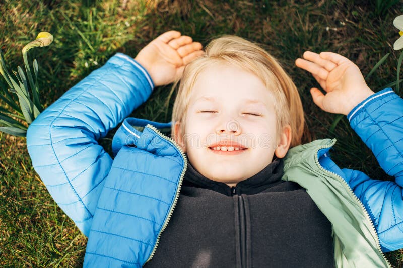 Blond Boy Lying in a Daffodil Field with a Dreamy Expression, Enjoying ...