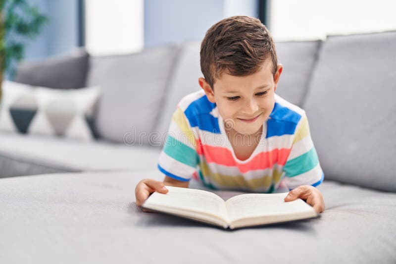 Blond Child Reading Book Sitting on Sofa at Home Stock Photo - Image of ...
