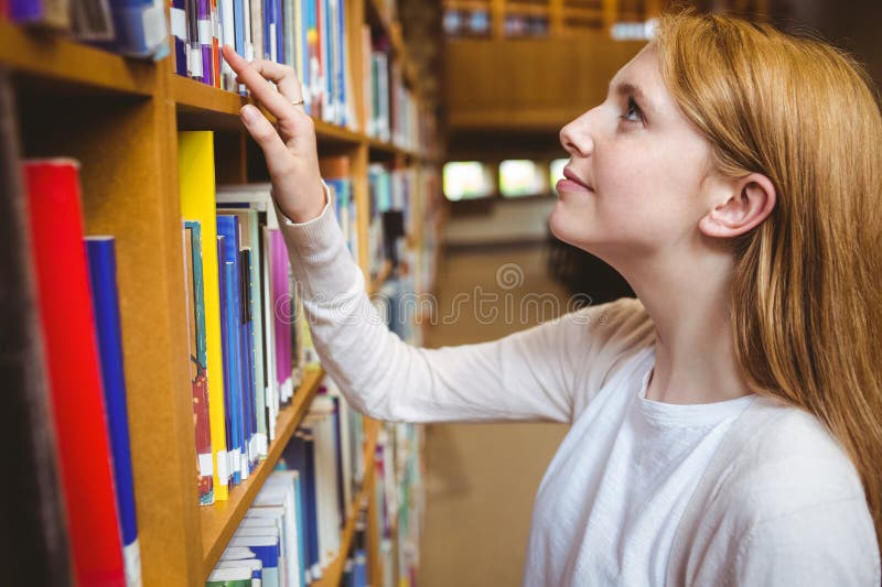 Teenage Girl Reaching for Book on Wooden Shelf in Library Aisle ...