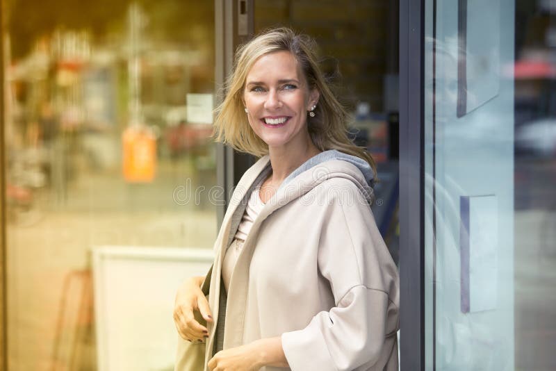 Blond Woman Walking Out of a Store Stock Image - Image of coat, blonde ...