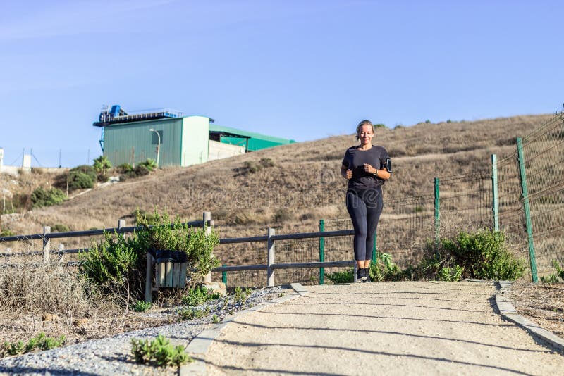 Blonde Athlete Woman Running Down a Path in the Field Stock Photo ...