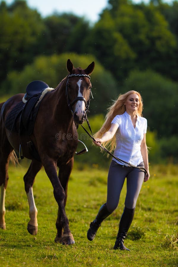 Blonde Frau Mit Langem Haarjockeyreiter Auf Einer Braune, in Einer ... Blonde Frau Mit Langem Haarjockeyreiter Auf Einer Braune, in Einer ...