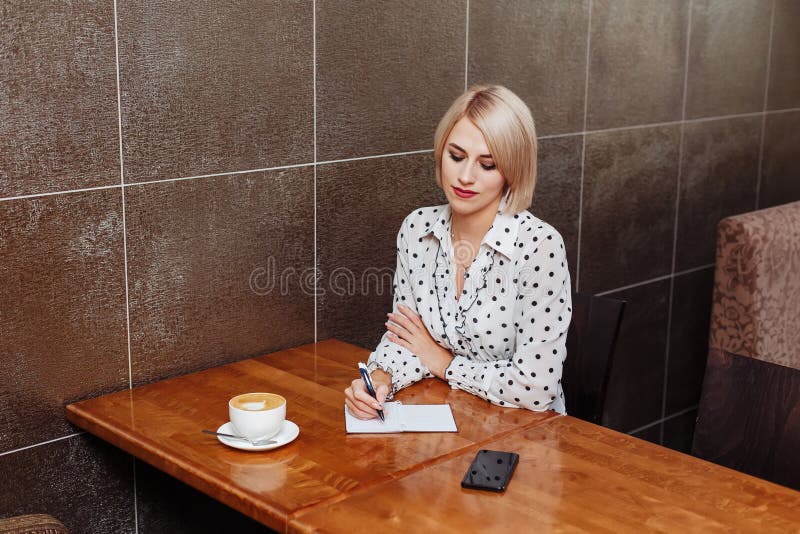 Blonde Woman in Cafe Writing in Notebook Stock Image - Image of table ...