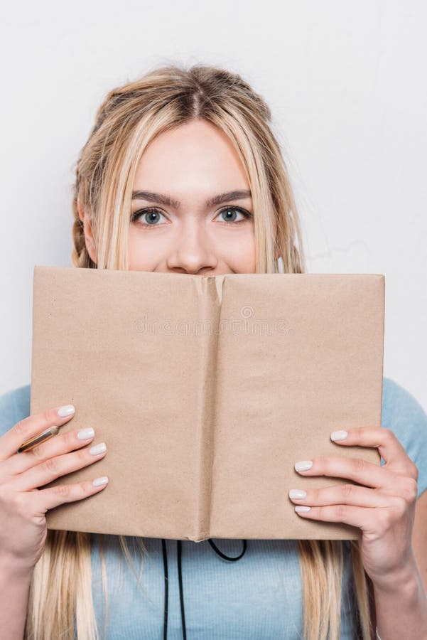 Blonde Woman Holding Book in Front of Face and Looking at Camera Stock ...