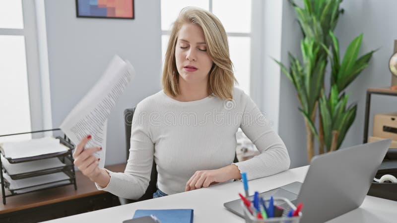 Blonde Woman Reviewing Documents in a Modern Office Setting, Evoking ...