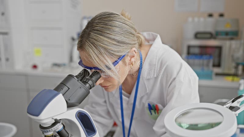 Blonde Woman Scientist Examining Specimen in Microscope at Indoor ...