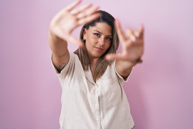 Blonde Woman Standing Over Pink Background Doing Frame Using Hands ...