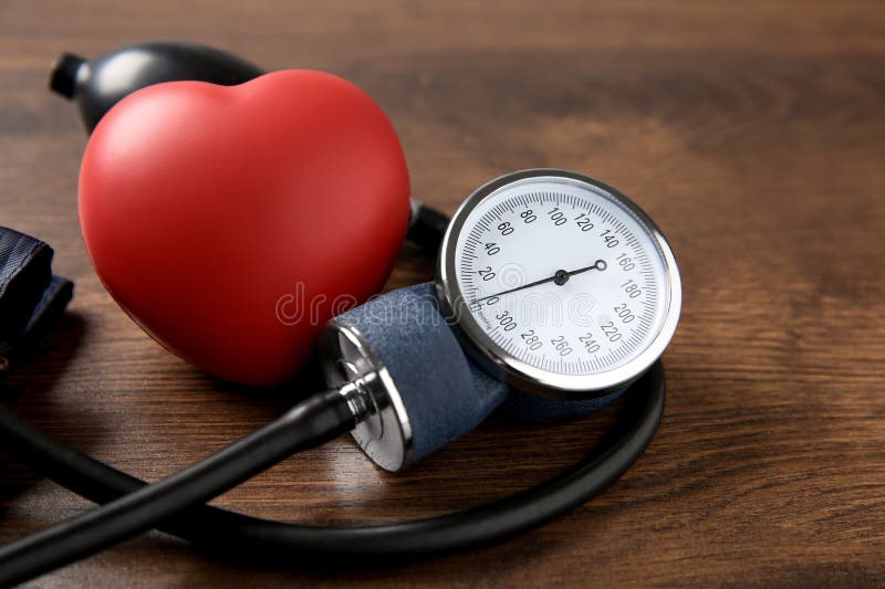 Blood Pressure Measuring Device and Squeeze Heart on Wooden Table ...