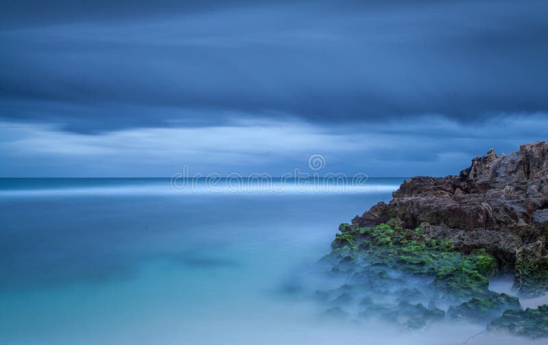 Blue beach scene with rock stock image. Image of overcast - 44095899
