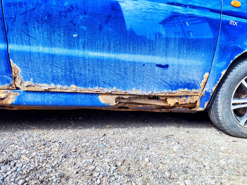 A Blue Car Shows Significant Rust Damage Along the Lower Side Panel ...