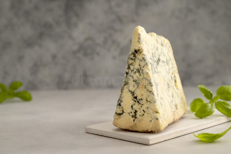 Blue Cheese Piece with Fresh Basil Leaves Over Gray Background. One ...