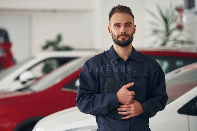 In Blue Colored Uniform. Car Repairman is in the Garage with Automobile ...