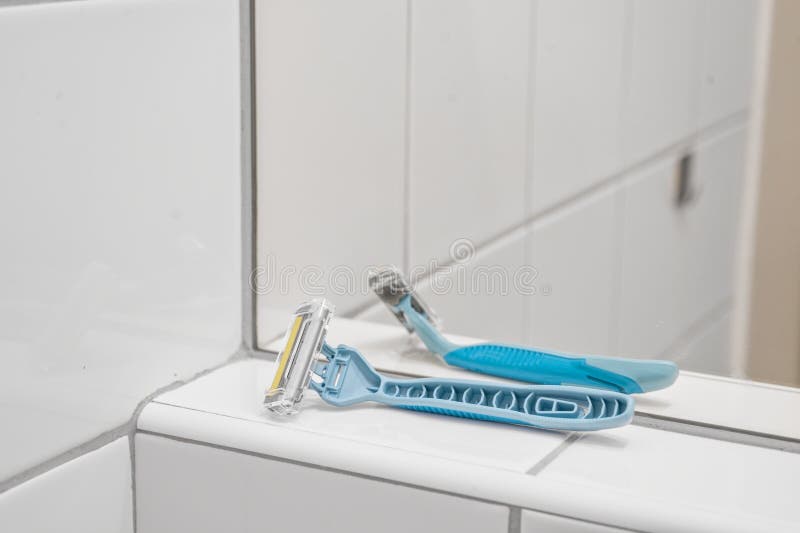 Blue Disposable Razor with Mirror Reflection on Bathroom Shelf Stock ...
