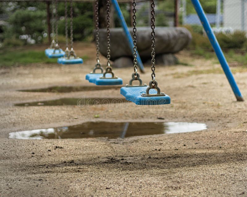 Blue Empty Swing Set with a Puddle in the Background. Stock Image ...
