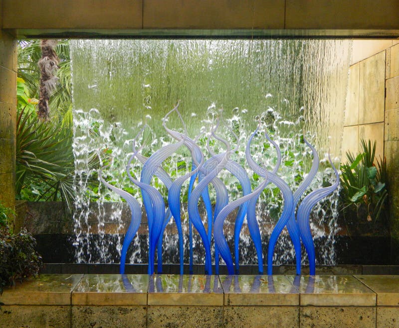 Blue Glass with Organic Shapes in Front of a Waterfall Displayed in a ...