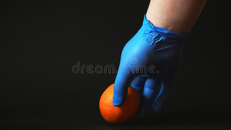 A Blue Gloved Hand Holds an Orange on a Black Background Stock Image ...