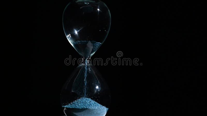 Hourglass with Blue Granules Spinning on a Black Background. Stock ...