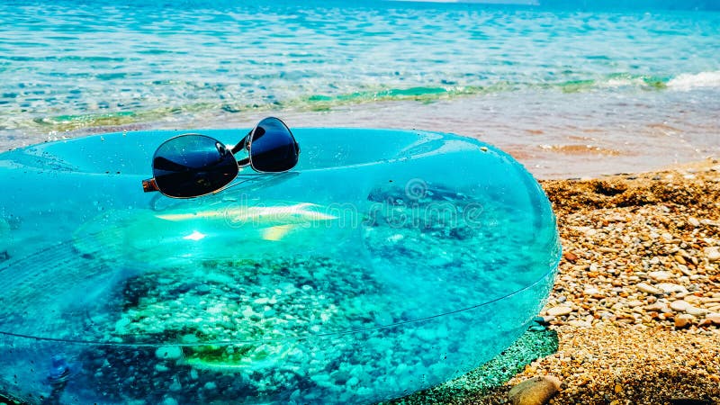 Blue Inflatable Swim Ring Float and Sunglasses on the Beach. Stock ...