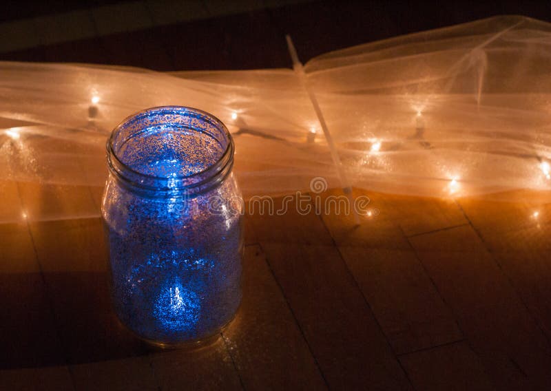 Blue Jar with a Light in Front of a Row of Material Covered White ...