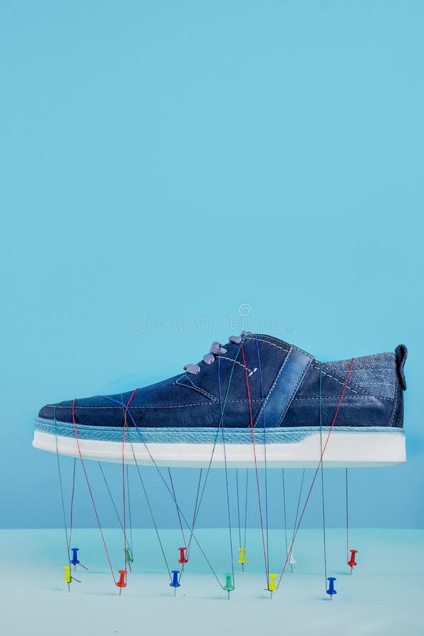 Blue Leather Men`s Sport Shoes Hanging on Colored Threads on a Blue ...