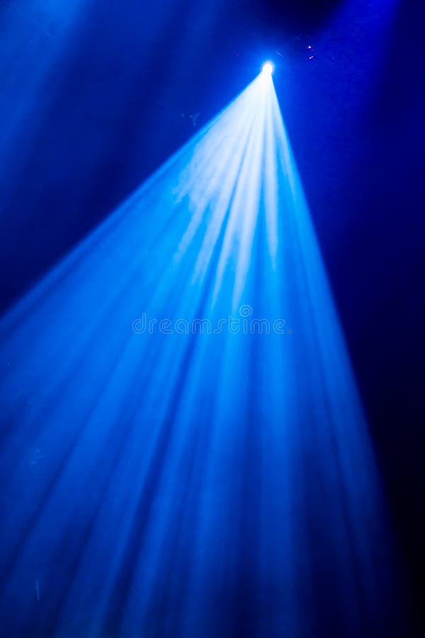 Blue Light Rays from the Spotlight through the Smoke at the Theater or ...