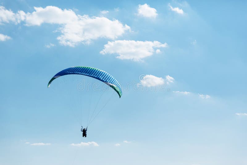 Blue Paraglider Flying into the Sky with Clouds on a Sunny Day Stock ...