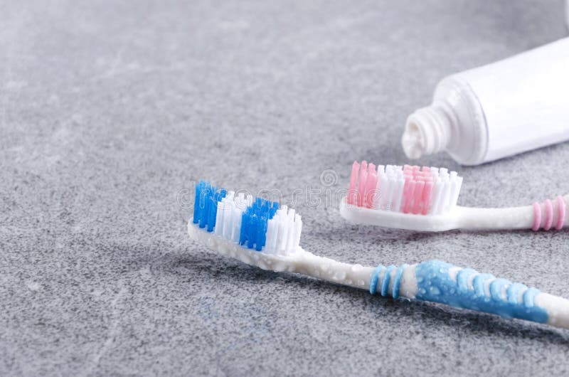 Blue and Pink Toothbrushes with Drops of Water on it and Toothpaste on ...