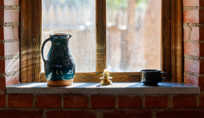 A Blue Pitcher Sits on a Window Sill Next To a Candle and a Cup Stock ...