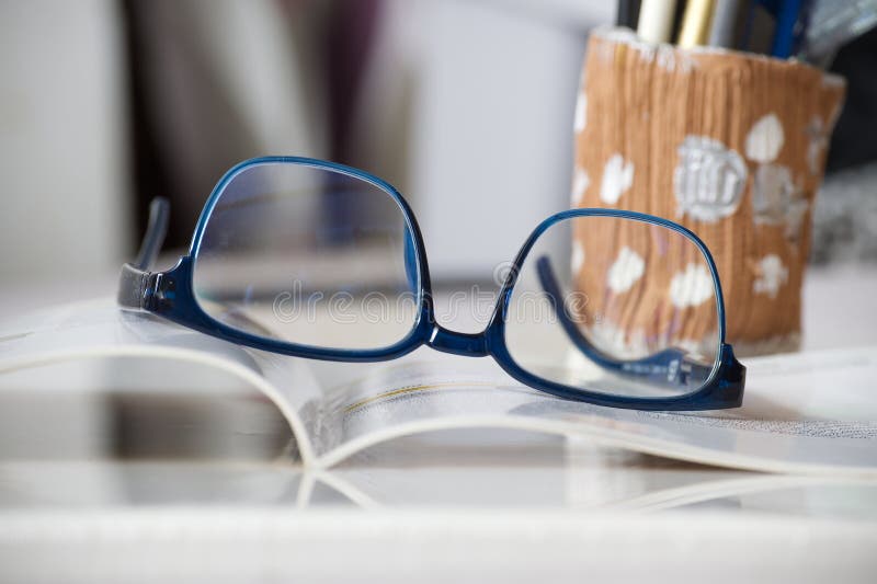 Blue Reading Glasses Resting on an Open Book in a Cozy Study ...