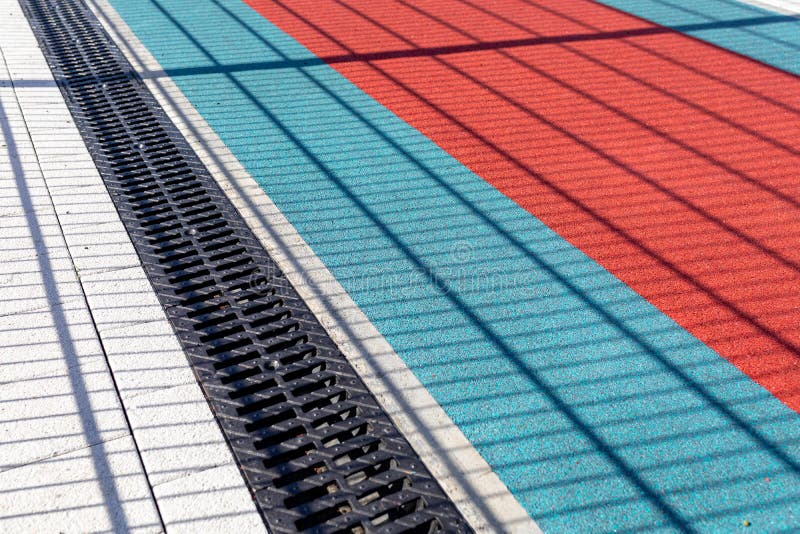 A Blue and Red Jogging Path Next To the Drainage and Pedestrian Area ...