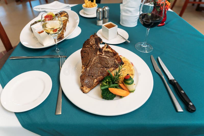 Blue Restaurant Dinner Table with Plates of Steak, Fish, and Wine Stock ...