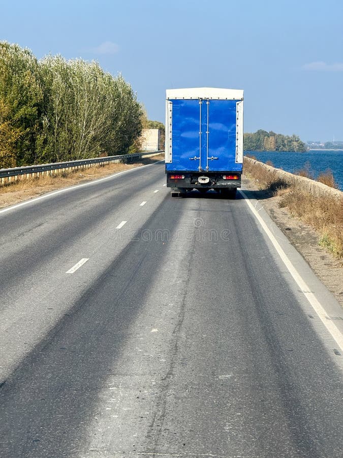 A Blue Semi Truck is Driving Down a Road with a Blue Trailer Stock ...
